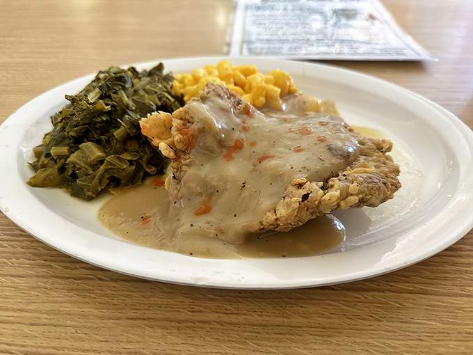 Behold the star attraction—chicken fried steak smothered in peppery gravy alongside greens and mac and cheese. This isn't a meal; it's a Southern revelation on a plate.