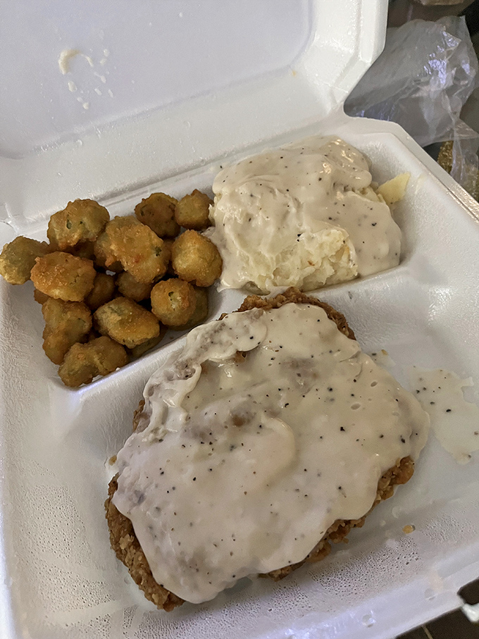 Behold the star of the show: chicken fried steak swimming in pepper-flecked gravy alongside golden-fried okra. Southern comfort in styrofoam form.