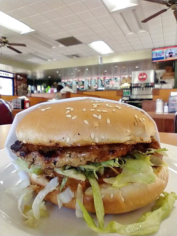 This isn't just a burger—it's a towering monument to beef artistry, where shredded lettuce cascades like a crunchy waterfall over a perfectly charred patty.