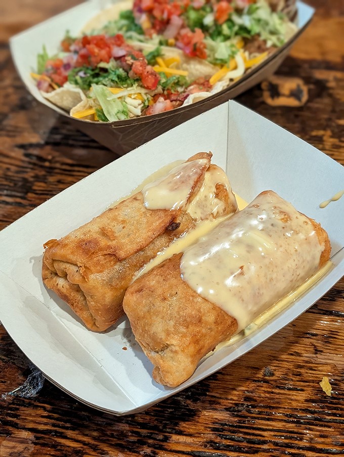 Golden-brown chimichangas draped in queso, served alongside a fresh taco salad – this plate has achieved what politicians cannot: perfect balance and universal appeal.