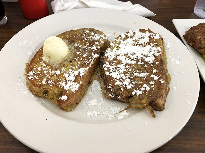 Two slices of French toast perfection dusted with powdered sugar. That pat of butter melting on top is performing a slow dance of deliciousness.