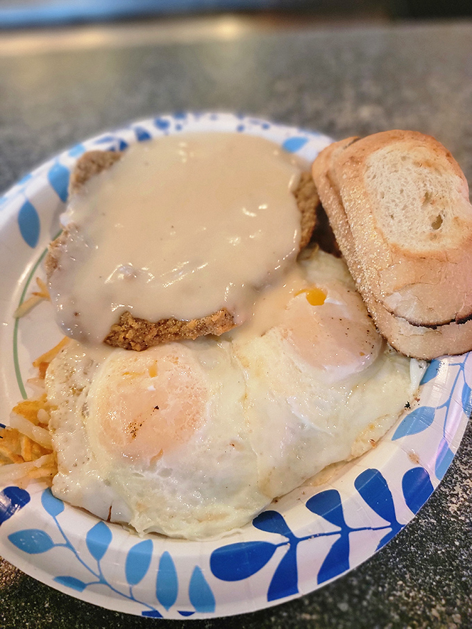 The country fried steak arrives like royalty, crowned with creamy gravy and accompanied by sunny-side-up eggs that wink at you from the plate.
