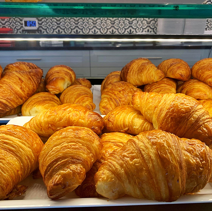 Golden-brown croissants stacked like treasure, their shatteringly crisp exteriors hiding honeycomb layers that took three days and countless butter prayers to create.