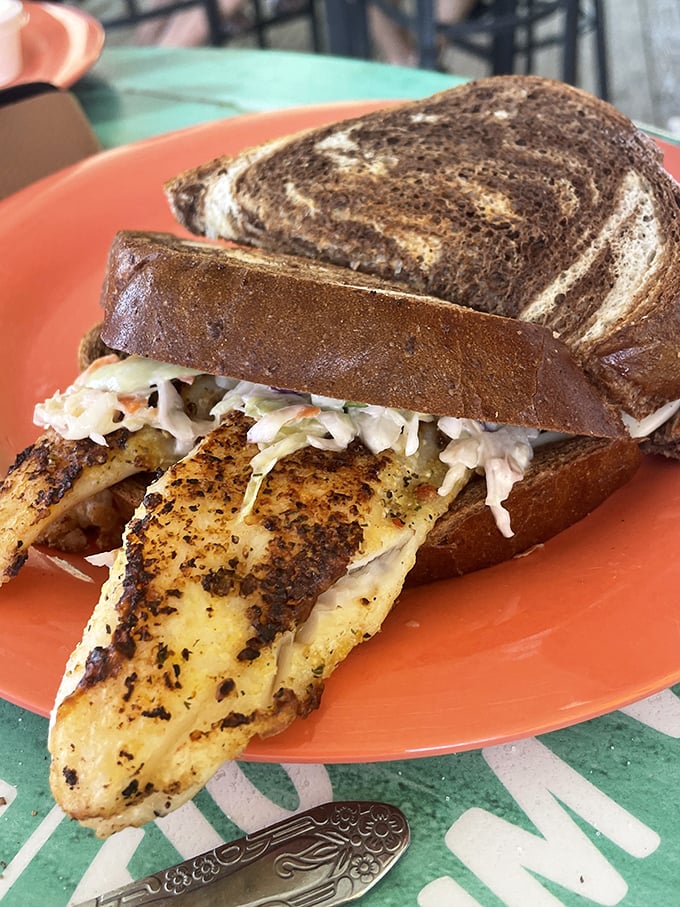 Blackened fish spilling out of marble rye like it's making a delicious escape attempt. The coleslaw isn't just a garnish&mdash;it's an essential co-conspirator.