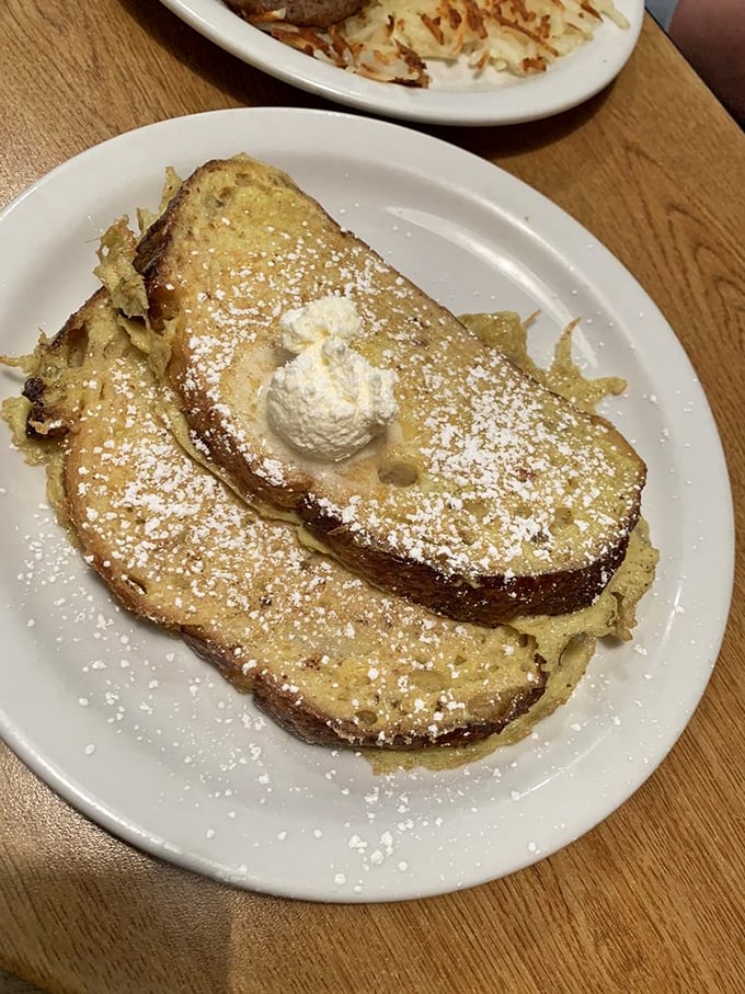 The French toast arrives like a powdered sugar snowfall on golden-brown perfection. That dollop of whipped cream isn't garnish&mdash;it's essential architecture.