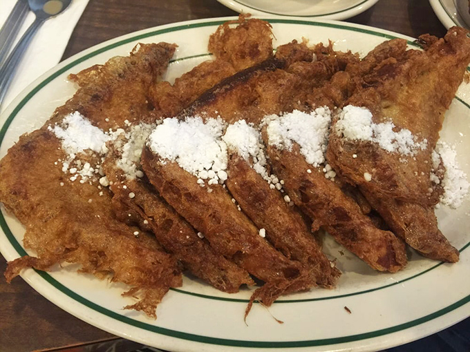 The French toast arrives looking like it just won a beauty pageant. Crispy exterior, custardy interior, and enough powdered sugar to make your dentist wince.