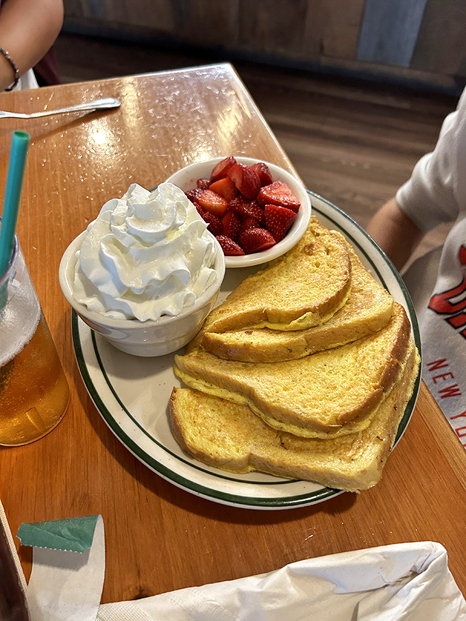French toast that's achieved celebrity status in New Hampshire. Golden slices nestled beside fresh strawberries and a mountain of whipped cream that defies gravity.
