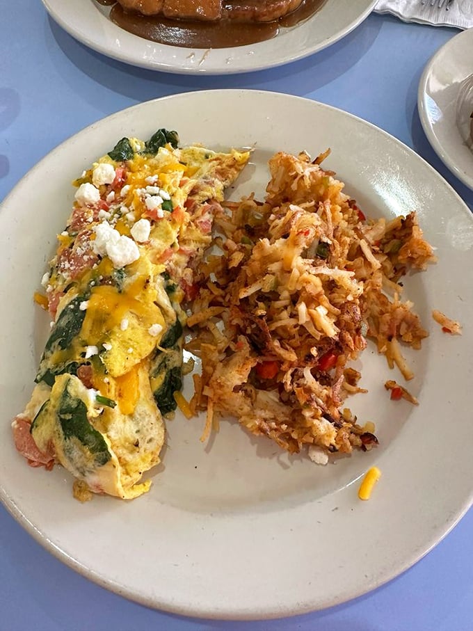 Behold the Greek omelet in its natural habitat &ndash; a plate barely containing its cheese-laden glory. Those hash browns deserve their own fan club.