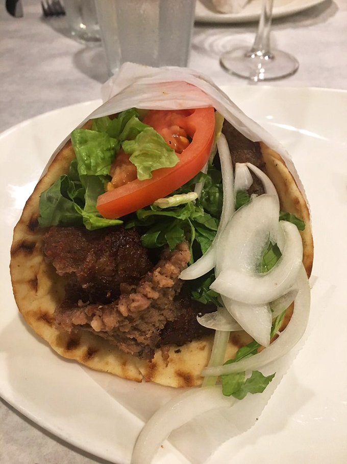A proper gyro isn't just a sandwich; it's architecture. This perfect stack of seasoned meat, fresh veggies, and pillowy pita is edible engineering.