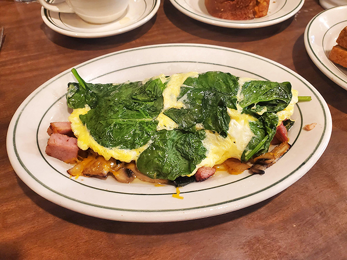 This isn't just an omelet; it's a masterpiece of morning architecture with spinach, ham, and cheese creating the breakfast equivalent of a standing ovation.