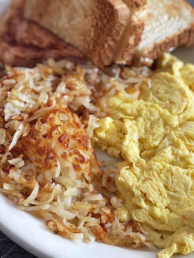 Behold the holy trinity of breakfast: golden hash browns with edges crisp enough to make a potato weep with pride.