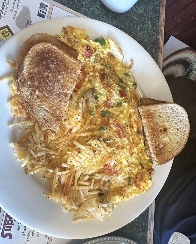 Breakfast nirvana achieved: golden hash browns sharing the spotlight with a perfectly executed omelet and toast ready for butter baptism.