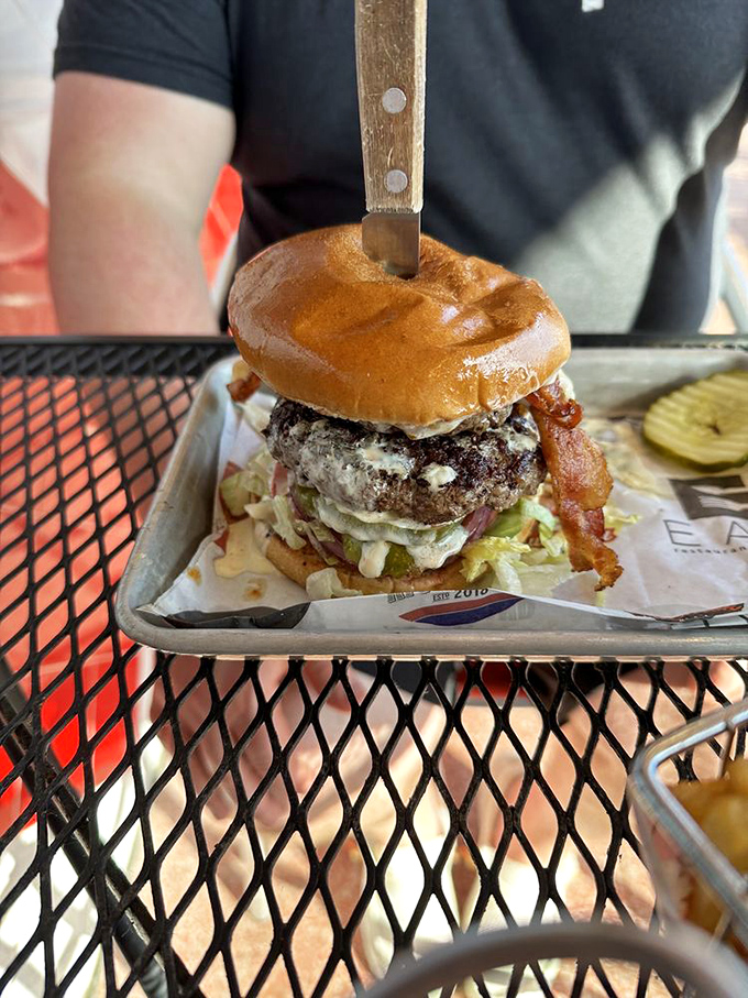 The knife isn't structural support&mdash;it's a dramatic pause before the flavor explosion. This burger demands both hands and your full attention.