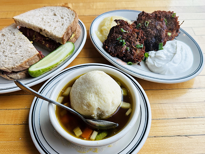 A trifecta of comfort: matzo ball soup floating like a cloud, latkes crisp as autumn mornings, and a sandwich that means business.