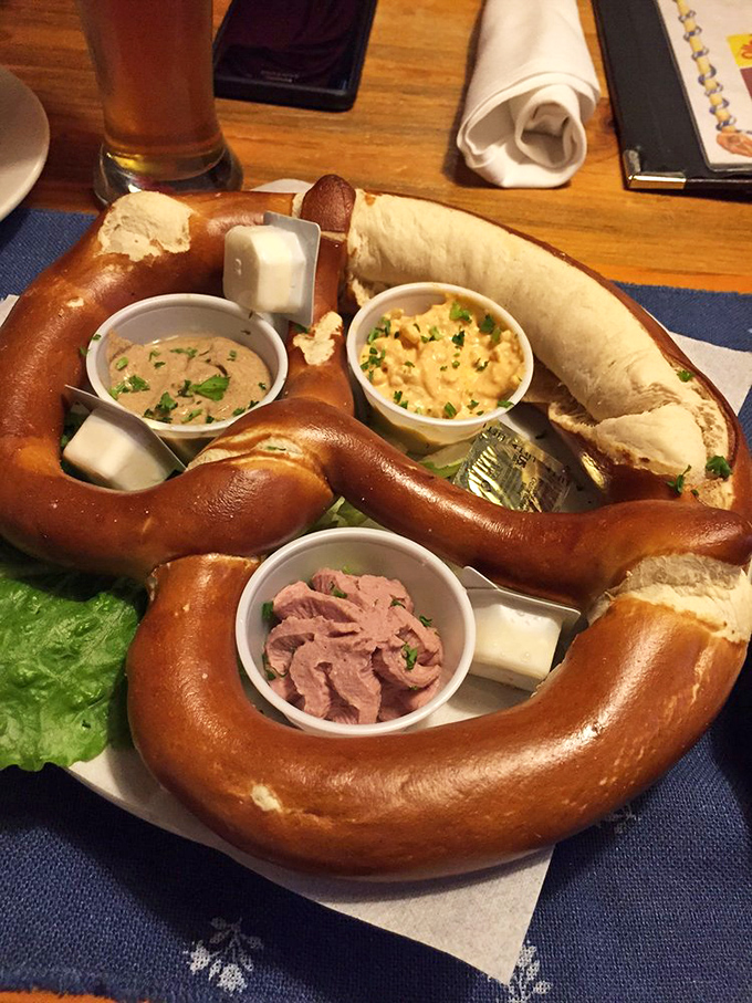 Behold the pretzel of your dreams! This golden-brown masterpiece arrives with three perfect dipping companions &ndash; beer cheese, mustard, and what appears to be liverwurst.