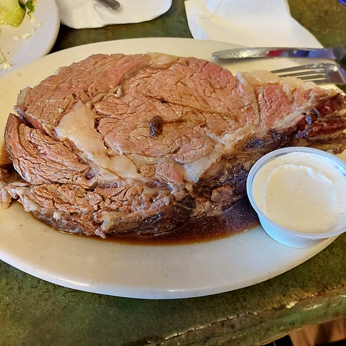 This prime rib isn't just dinner; it's a monument to patience and proper aging, served with a side of beef jus that's practically drinkable.