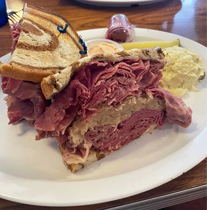 Behold the architectural marvel that is The Bagel Deli's Reuben – a skyscraper of corned beef requiring structural engineering skills just to take the first bite.