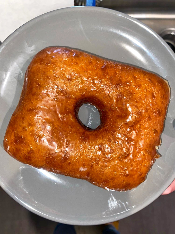The glazed square donut catches light like stained glass in a cathedral of carbs. Its amber surface promises a honeyed crunch giving way to tender interior.