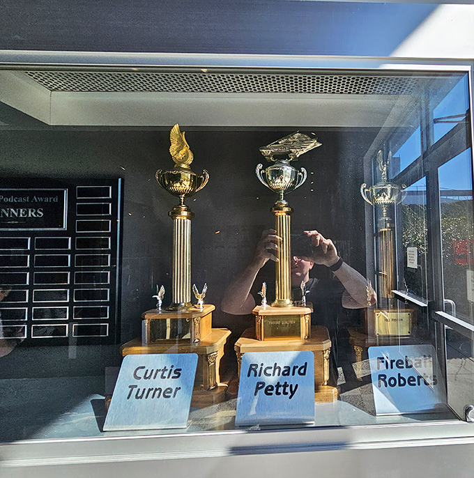 Trophy case featuring racing's holy grail&mdash;hardware earned by legends like Richard Petty. Some people collect stamps; these folks collected checkered flags.