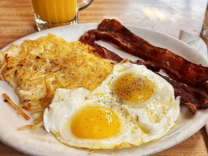 Breakfast perfection on a plate: crispy hash browns, sunny-side-up eggs with that ideal runny yolk, and bacon cooked to that magical crisp-yet-chewy state.