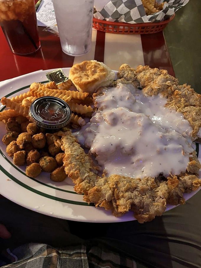 Behold: the chicken fried steak in its natural habitat, surrounded by crispy companions and a biscuit that didn't come here to play.