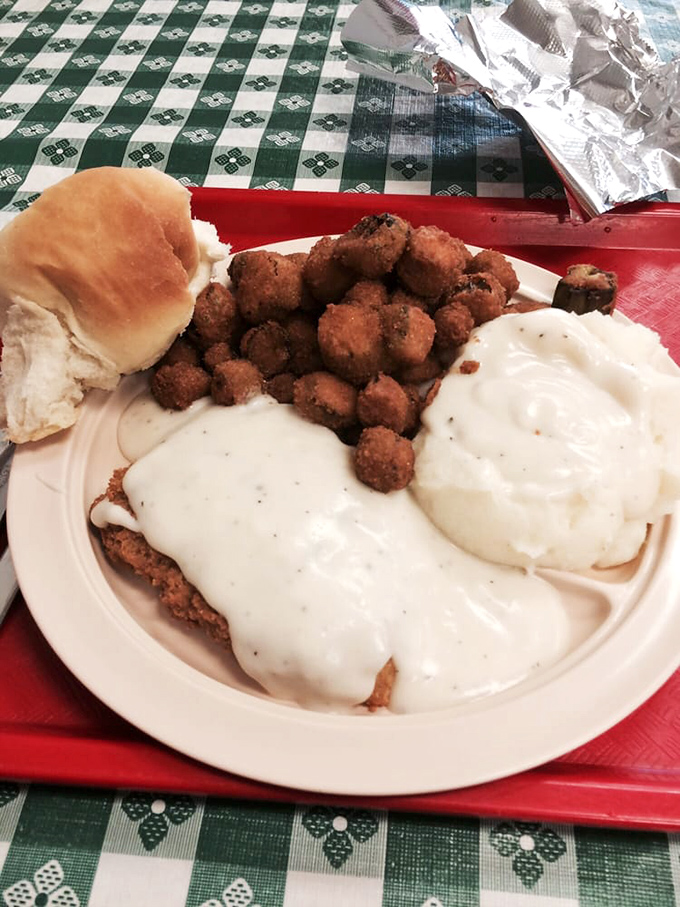 This chicken fried steak doesn't just hang over the plate—it establishes dominion over it, crowned with gravy that could make a vegetarian reconsider.