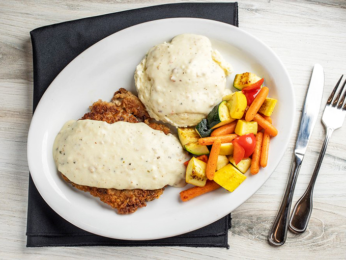 Behold the star of the show: chicken fried steak smothered in pepper-flecked gravy alongside fluffy mashed potatoes and colorful vegetables.