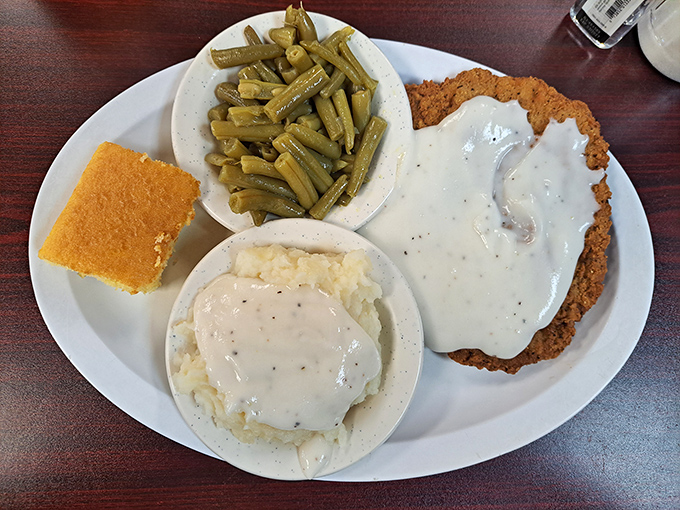 Southern poetry on a plate: country fried steak bathed in pepper gravy alongside mashed potatoes, green beans, and cornbread. Grandma would approve.