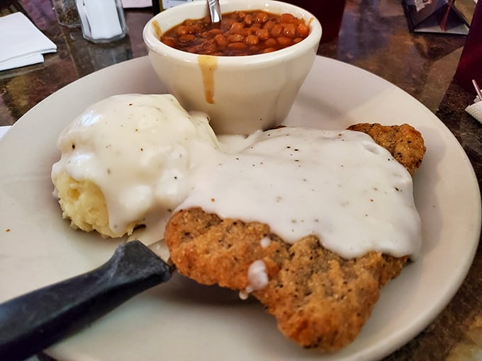 Southern comfort on a plate: chicken fried steak smothered in peppery gravy alongside creamy mashed potatoes and baked beans. Grandma would approve.