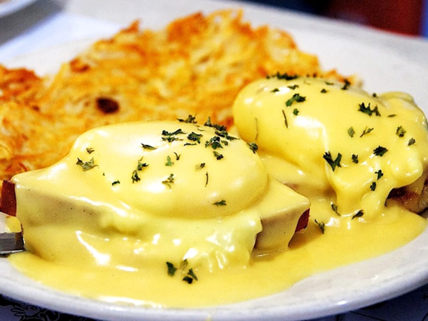 Eggs Benedict that would make royalty jealous. That hollandaise sauce cascades like a golden waterfall over perfectly poached eggs.