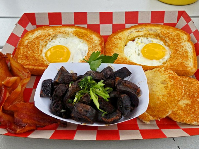 Breakfast perfection on a red checkered plate&mdash;eggs nestled in toast with a side of those legendary dark-roasted potatoes that haunt your dreams.