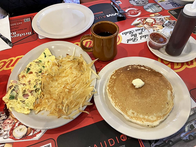 Breakfast perfection on a plate: golden pancakes, a fluffy omelet bursting with fillings, and hash browns crispy enough to make a potato proud.