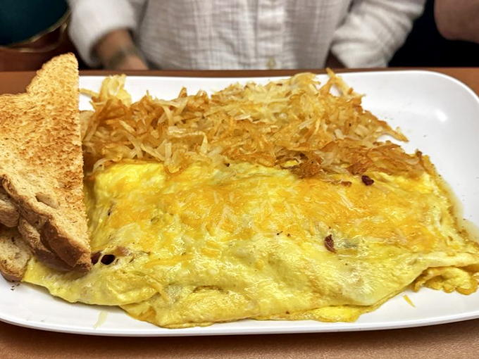 This isn't just any omelet—it's a fluffy golden pillow of breakfast perfection, hash browns crispy enough to make a potato proud.