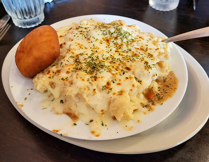 Behold the star attraction &ndash; shepherd's pie with a golden-brown crust that crackles with promise. That side roll isn't just carb companionship; it's essential gravy-sopping equipment.