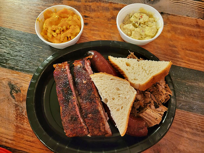 The holy trinity of barbecue: ribs with that beautiful char, tender pulled pork, and two sides that know their supporting role. White bread included, as tradition demands.