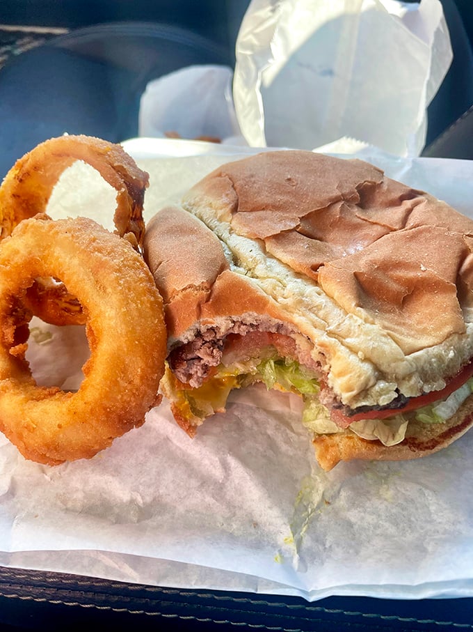 The holy trinity of diner perfection: a perfectly constructed burger with all the fixings, golden onion rings, and that paper wrapping that says "the real deal."