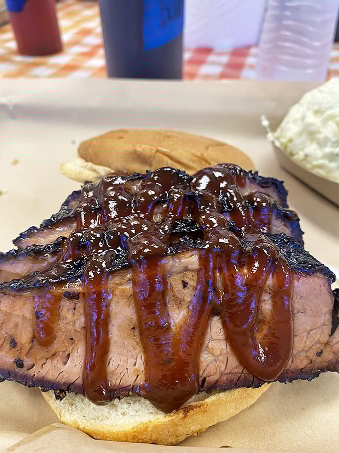 The brisket sandwich that makes vegetarians question their life choices. That glistening sauce cascade is what barbecue dreams are made of.