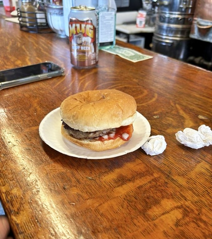 The classic American trinity: a perfect burger, root beer, and a wooden counter that tells stories with every scratch and stain.
