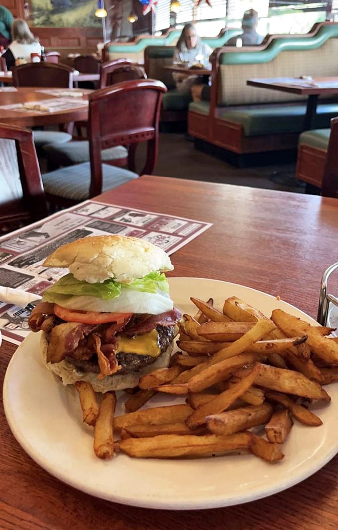 Architecture of deliciousness: a towering burger with bacon and cheese that requires both hands, strategic planning, and absolutely no first-date nerves.