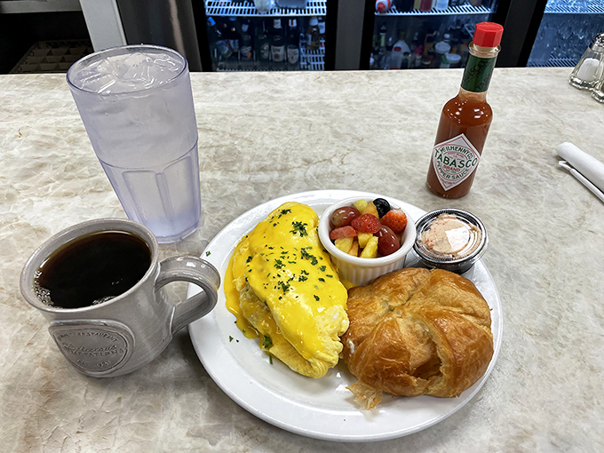This isn't just an omelet – it's a breakfast masterpiece with fresh fruit and a buttery croissant that would make a Parisian weep with joy.
