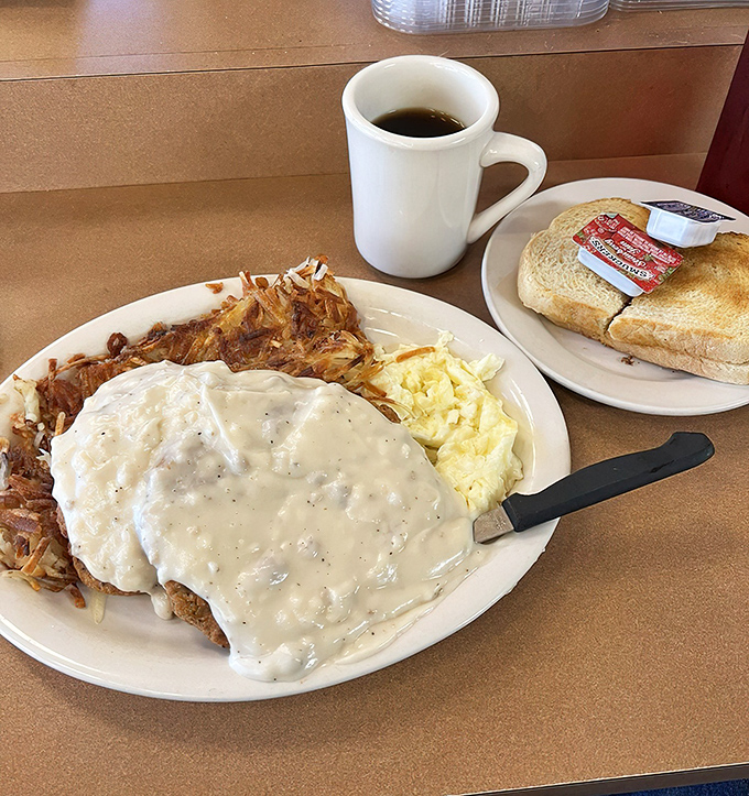 The holy trinity of diner perfection: chicken fried steak smothered in peppery gravy, buttery toast, and coffee strong enough to jumpstart your day.