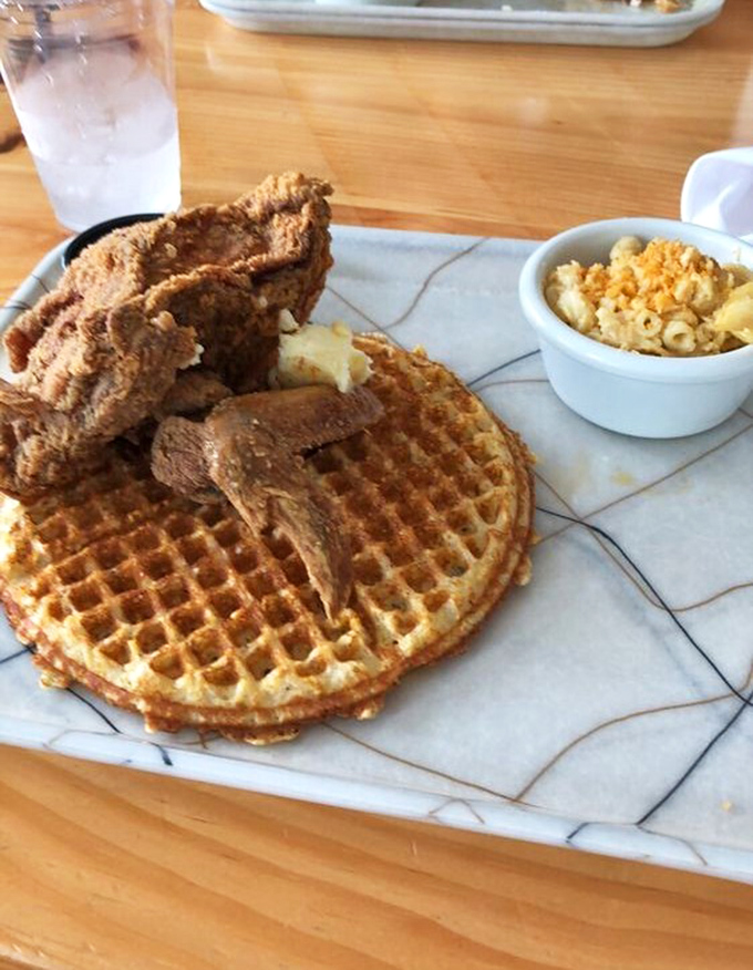 The holy trinity of comfort: crispy fried chicken, buttery waffle, and mac and cheese that would make your grandmother both jealous and proud.