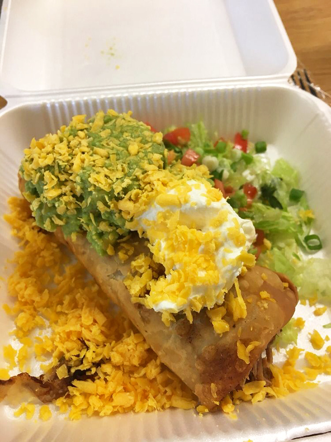The chimichanga in its natural habitat&mdash;crispy exterior giving way to savory filling, topped with the holy trinity of sour cream, guacamole, and shredded cheese.