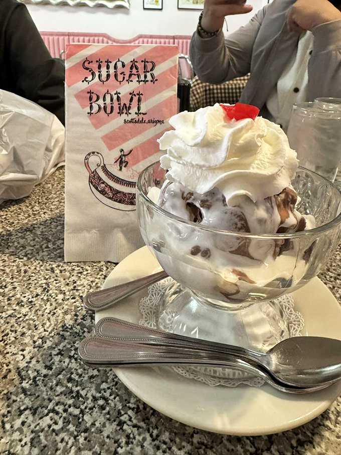 This isn't just dessert, it's architecture—layers of ice cream and toppings creating a skyline of sweetness against the pink booth backdrop.