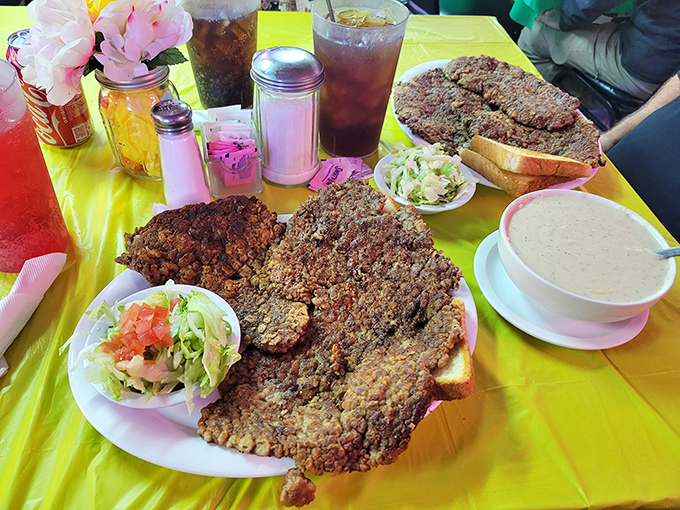 Two plates of chicken fried steak that could double as throw rugs, accompanied by gravy boats you could practically sail away in.