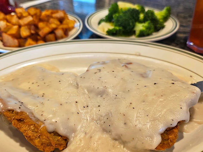 Behold the crown jewel: country fried steak smothered in peppery gravy that cascades like a savory waterfall over crispy, golden perfection.