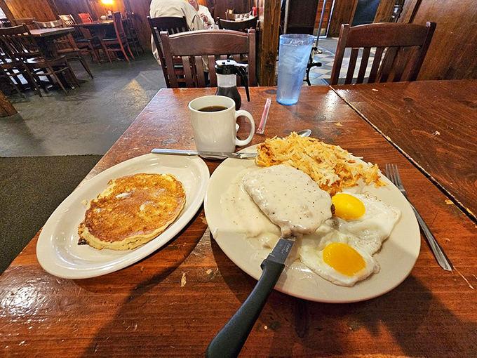 Breakfast of champions! Country fried steak smothered in pepper-flecked gravy alongside sunny-side-up eggs and hash browns that crackle with each bite.