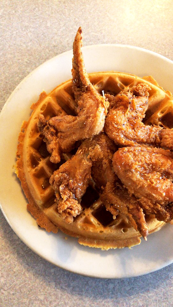 Close-up magic! Perfectly fried chicken wings huddle on a golden waffle, creating a sweet-savory love story on a plate.