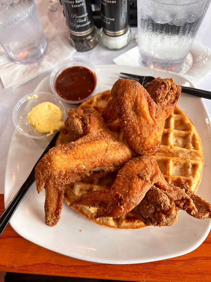 Crispy wings nestle against a golden waffle, with schmear and syrup standing by like loyal sidekicks ready to elevate each bite to superhero status.