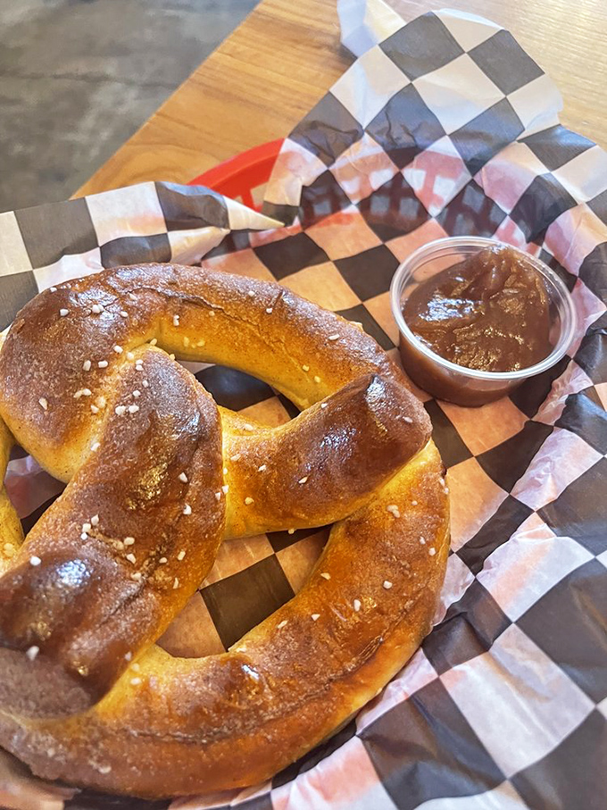 A pretzel stick with dipping sauce served on classic blue and white checkered paper &ndash; proof that simplicity often delivers the most profound satisfaction.